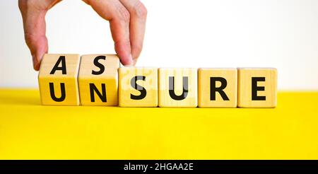 Assure or unsure symbol. Businessman turns wooden cubes and changes the ...