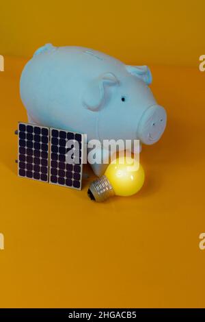 Piggy bank, yellow lamp and photovoltaic solar energy panel isolated on yellow background Stock ...