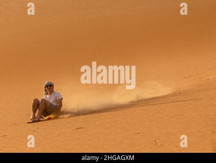 Tourist making sandboarding in the Rub al Khali dunes desert, Najran ...