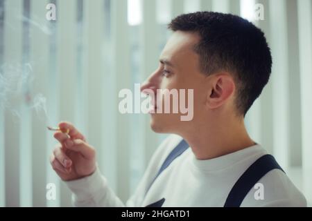 Portrait of a man smoking in a smoking cubicle. Cigarette smoking area ...