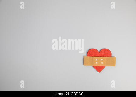 Heart with medical patch on grey background, top view. Relationship ...