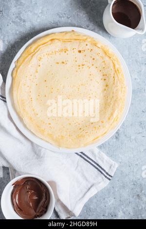 Crepes pancakes formed in pyramid shape on a blue plate in bright ...
