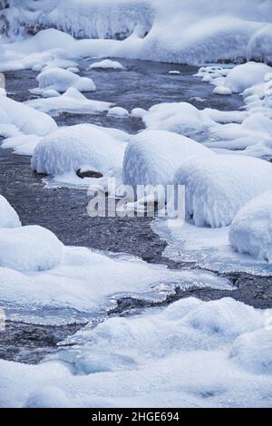 Photo of Stones with snow caps and ice in the water of frozen river ...
