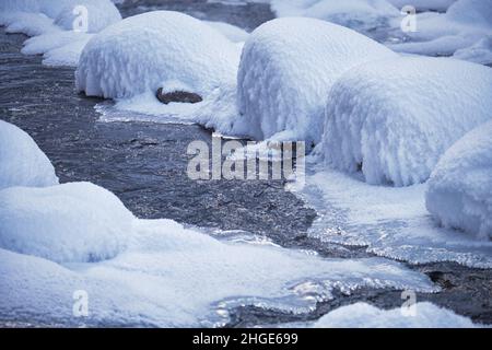 Photo of Stones with snow caps and ice in the water of frozen river ...