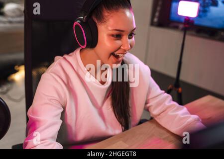 Happy young woman streamer gamer in headphones playing online games on ...