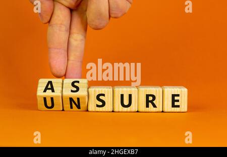 Assure or unsure symbol. Businessman turns wooden cubes and changes the ...