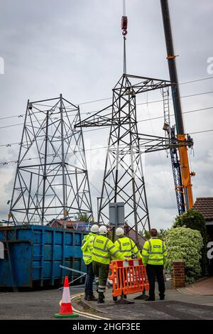 Workers replacing high voltage electricity cable on a pylon using ...