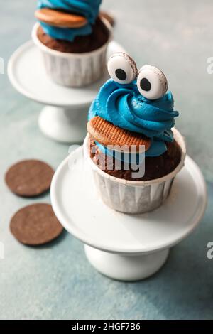 Stand with tasty funny cupcake for Halloween celebration on color ...
