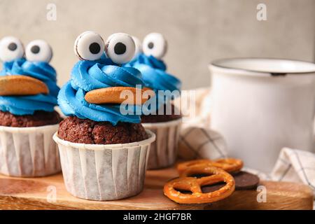 Board with tasty funny cupcakes for Halloween celebration on table ...