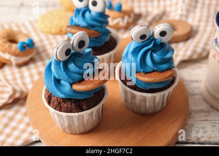Board with tasty funny cupcakes for Halloween celebration on table ...