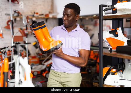 Man chooses rubber boots at garden supply store Stock Photo - Alamy