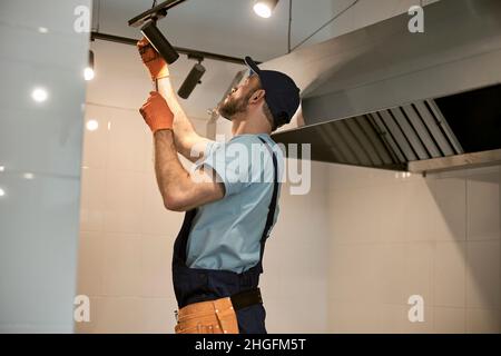 Repairman fixing ceiling lamp in cafe kitchen Stock Photo - Alamy