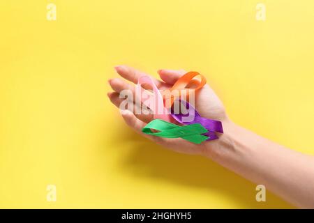 Female hand with different awareness ribbons on pink background ...