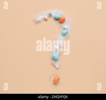 Question mark made of feathers and decorative eggs on color background ...