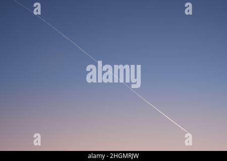 White diagonal aircraft trace on clear gradient evening sky after ...