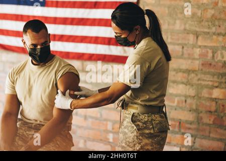 Female medic placing a band aid on a soldier's arm in the military ...