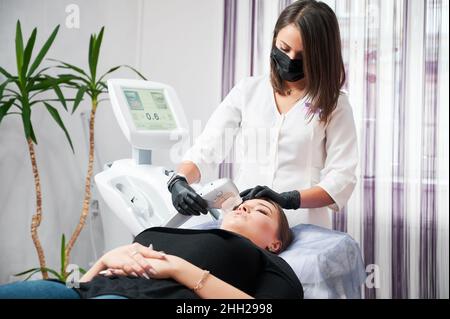 Female aesthetician in protective face mask discussing with woman at ...