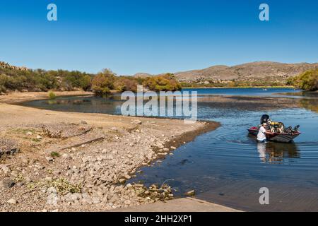 Man wading, pushing speedboat to boat ramp on Arivaca Lake, Atascosa ...