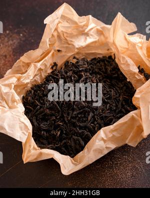 Dry tea leaves for black tea and paper tea bag on wooden background ...