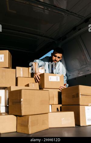 Male picking up box from shelf in distribution warehouse Stock Photo ...