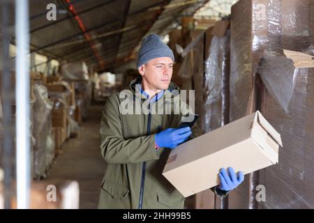 Store worker scans qr code on boxes using smartphone in warehouse shop ...
