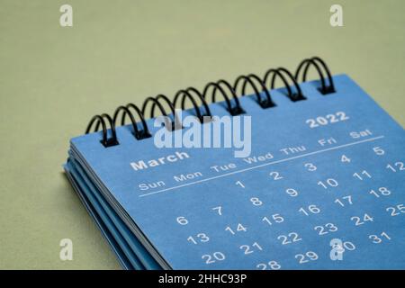 March 2022 - spiral desktop calendar with a stack of old book against ...