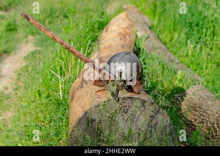 View of ancient Viking armor lying on a wooden log. Helmet and ax ...