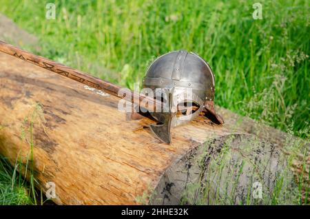 View of ancient Viking armor lying on a wooden log. Helmet and ax ...