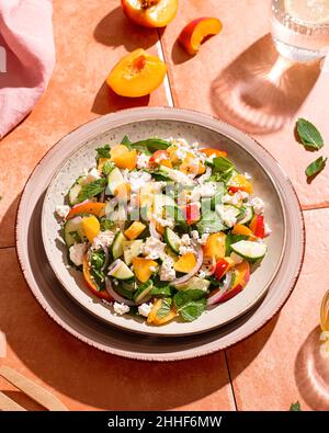 Peach and cheese salad with dressing and herbs on terracotta tile table ...