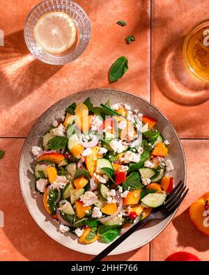 Peach and cheese salad with dressing and herbs on terracotta tile table ...