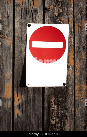 A circular red sign with a white bar indicating NO ENTRY on a grey ...