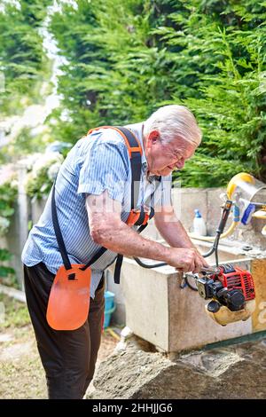 Concentrated elderly male gardener fixing mechanism of broken lawn ...