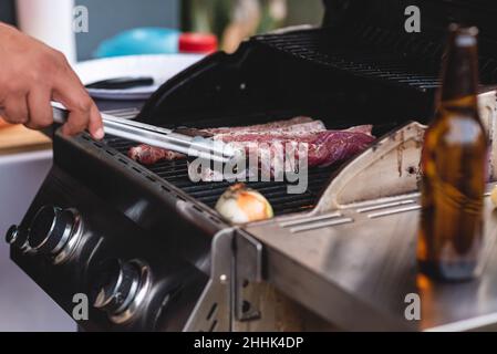 Cropped unrecognizable male in apron placing raw marinated meat on ...