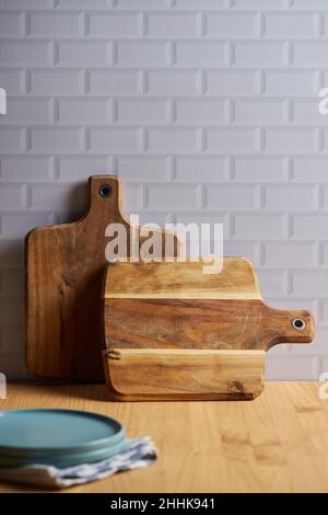 Wooden chopping boards placed near wall on table with bowl in light ...