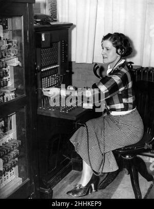 1930s WOMAN TELEPHONE OPERATOR AT SWITCHBOARD LOOKING AT CAMERA SMILING ...
