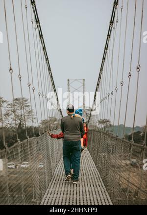 People walking on a hanging bridge, crossing over Bahorok river in ...