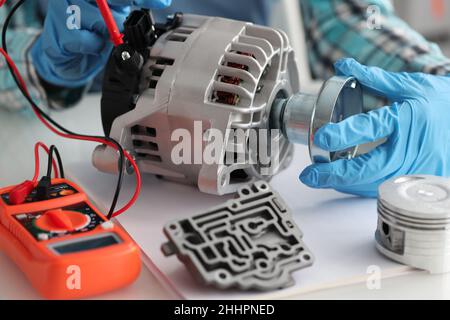 Master repairman diagnosing breakdown of car generator using tester ...