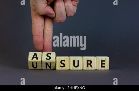 Assure or unsure symbol. Businessman turns wooden cubes and changes the ...