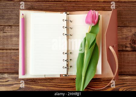 Composed notepad with pen on wooden table with plastic wineglass in ...