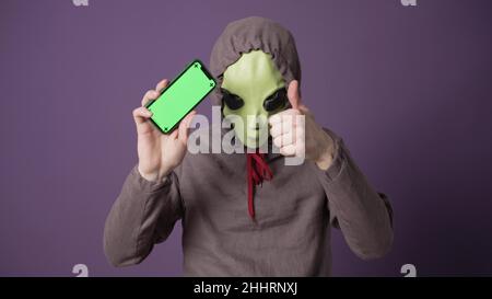 Alien wearing purple hoodie with hood laces tied tight under chin ...
