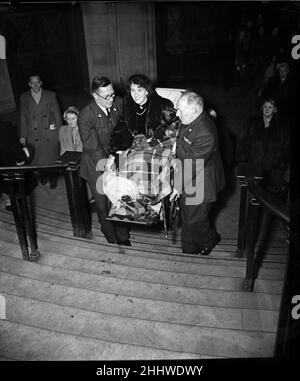 Authoress Enid Blyton in hospital lying in bed comforted by her husband ...