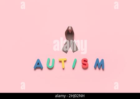 Word AUTISM with awareness ribbon on pink background Stock Photo - Alamy