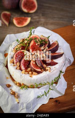 Brie cheese served on a wooden board with figs, walnuts and honey Stock ...