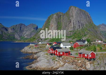 Red rorbuer on a stony shore, fishing boats, high, rugged mountains ...