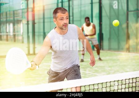 Athletic mens plays padel. View through tennis net Stock Photo - Alamy