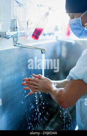 Young female worker sanitizing hands with alcohol based antibacterial ...