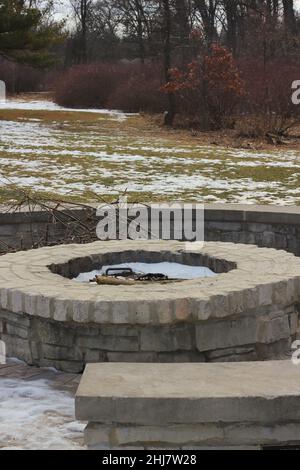 Stone campfire ring with a fireplace, logs, and seating Stock Photo - Alamy
