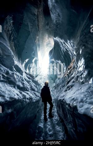 A man explores inside an ice cave in the Erebus Glacier, Antarctica ...