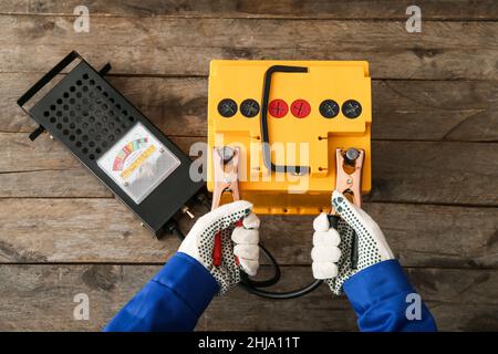 Man testing car battery on wooden background Stock Photo - Alamy