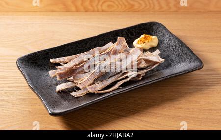 Dried squid and mayonnaise placed on a black background. Surume is a ...